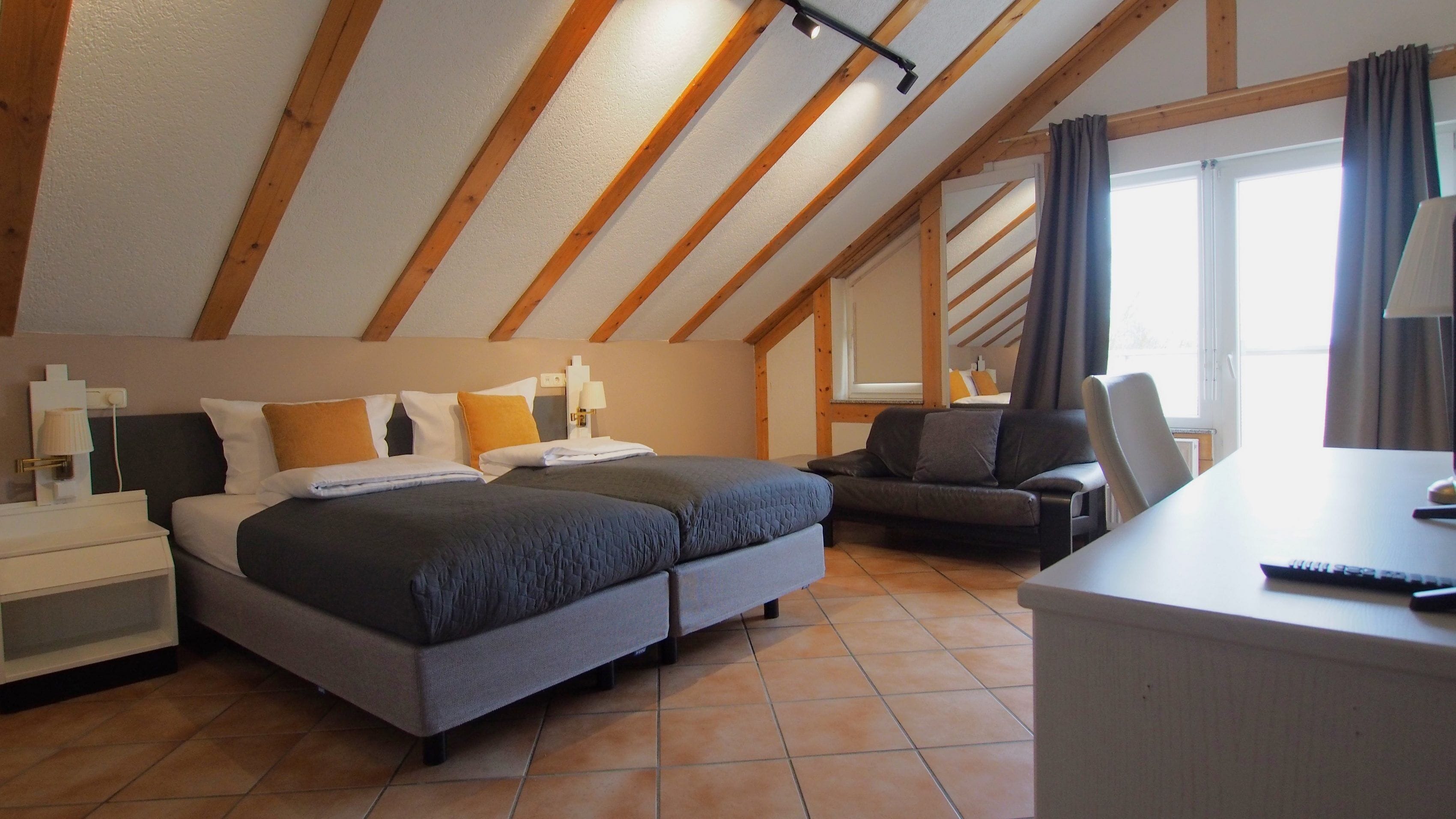 Um quarto com cama, escrivaninha, cadeira e sofá.