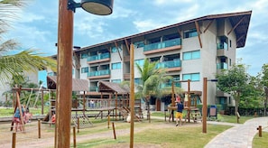 Um hotel com vários andares e áreas de lazer ao ar livre, incluindo uma estrutura de escalada de madeira e balanços.