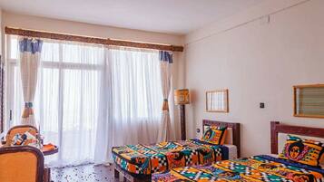 Quarto de hotel com duas camas, uma mesa e uma cadeira.