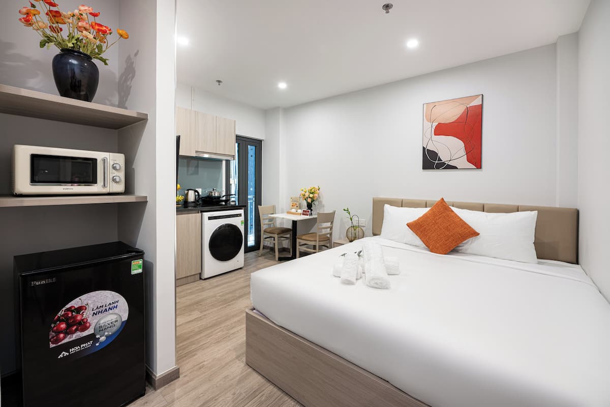 Quarto de hotel com cama, micro-ondas, máquina de lavar roupa e uma pequena área de refeições.