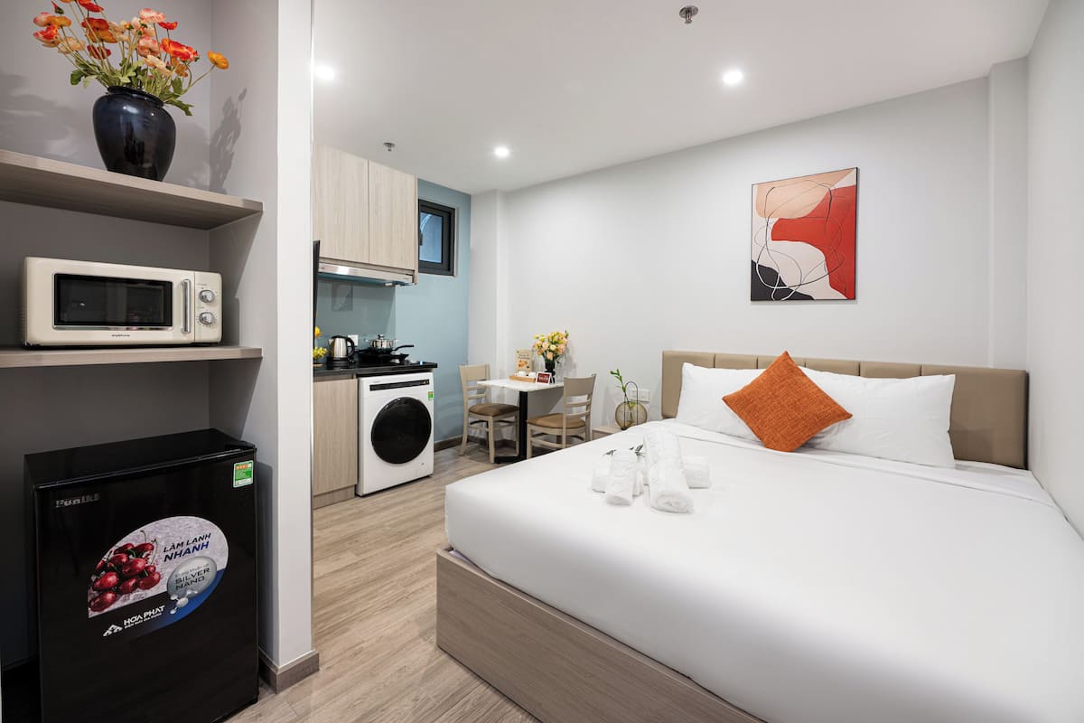 Quarto de hotel com cama, micro-ondas, máquina de lavar e área de refeições.