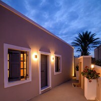 Um edifício moderno com fachada plana, vários acessos e iluminação exterior.
