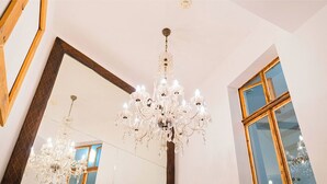 Um candelabro numa sala com janelas amplas e um espelho refletindo o candelabro.