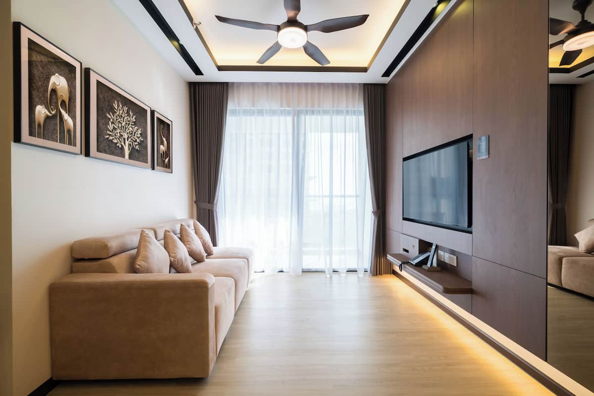 Uma sala de estar moderna com sofá, televisão de tela plana e ventiladores de teto.