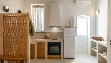 Uma cozinha compacta com forno embutido, geladeira e uma janela com cortinas.