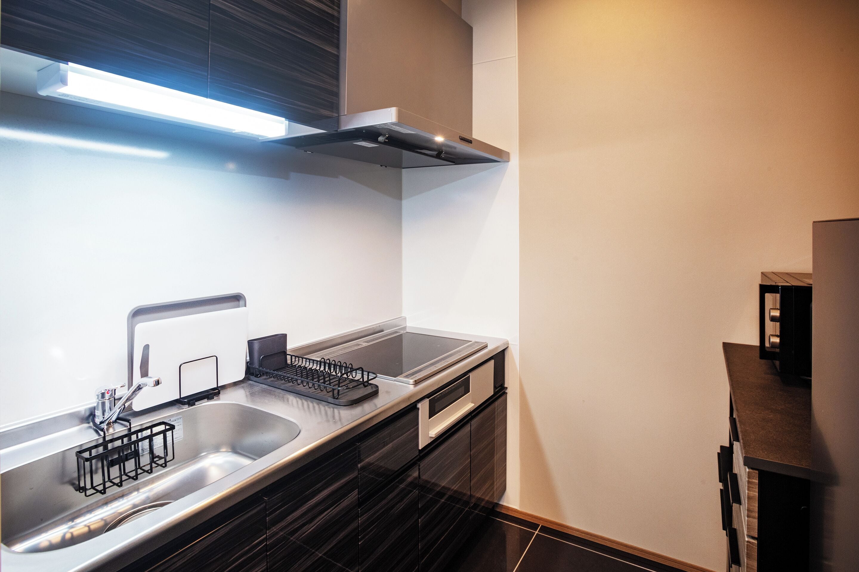 Cozinha moderna com pia de aço inoxidável, bancada preta e forno embutido.