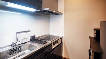 Cozinha moderna com pia de aço inoxidável, bancada preta e forno embutido.