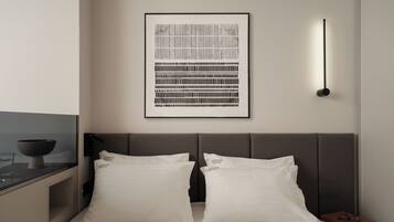 Quarto bem arrumado com cama, almofadas, mesa de cabeceira e luminária na parede.