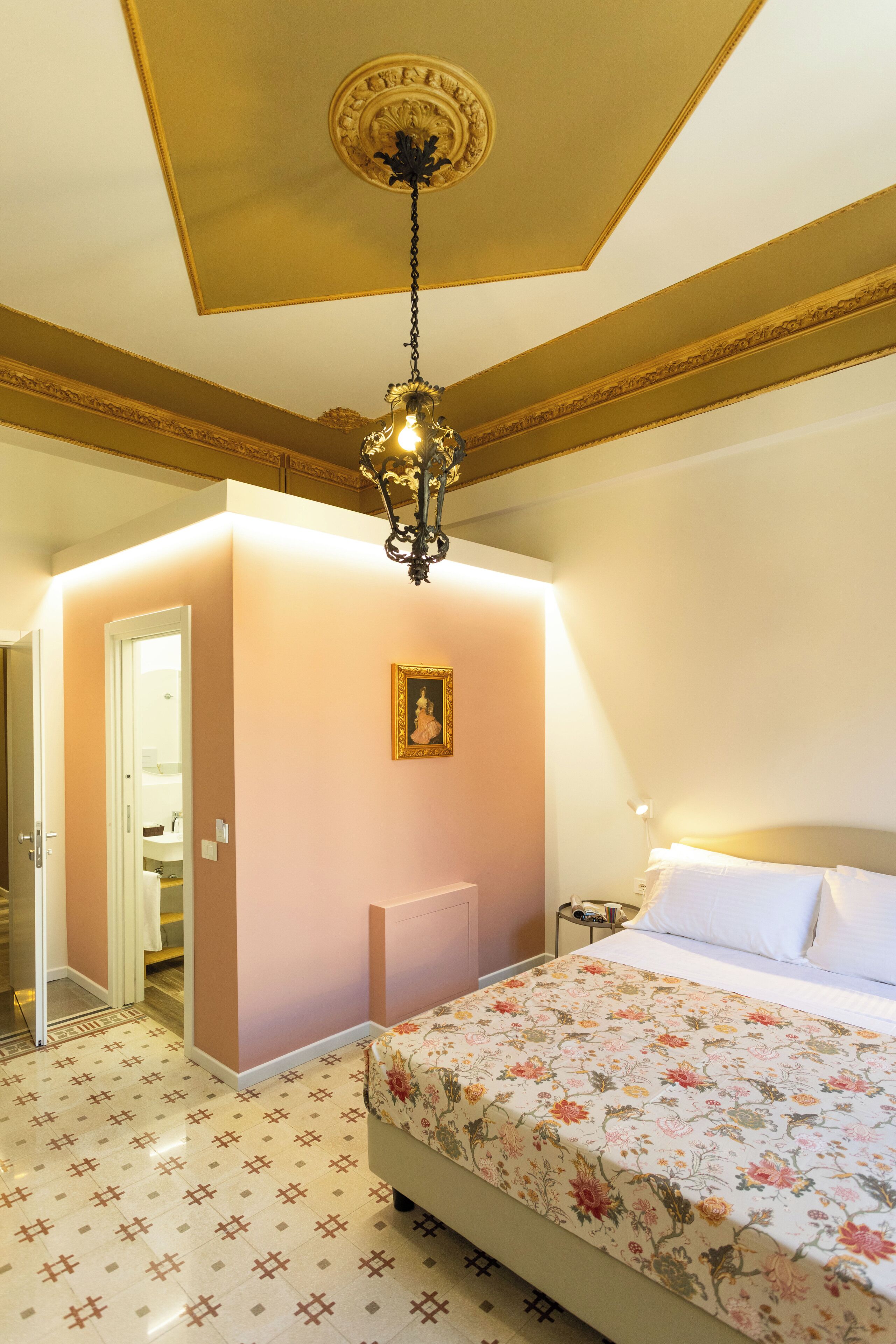 Quarto com cama, mesa de cabeceira, quadro na parede e luminária no teto.
