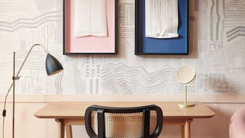 Um quarto com uma escrivaninha de madeira, uma cadeira, um abajur e duas obras de arte emolduradas na parede.