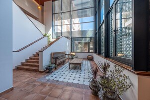 Um espaço amplo em ambiente interno com escada, um banco de madeira e plantas em vasos.
