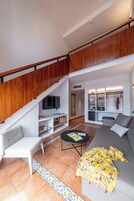 Uma sala de estar moderna com escada, sofá, mesa de centro e televisão.