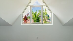Um claraboia triangular com vista para plantas em vasos e um edifício lá fora.
