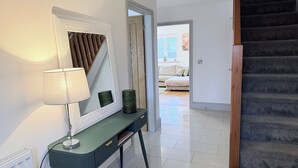 Um corredor moderno com um console, um espelho e uma escada.