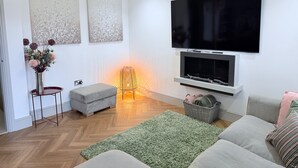 Uma sala de estar moderna com televisão de tela plana, lareira e um espaço de estar aconchegante.
