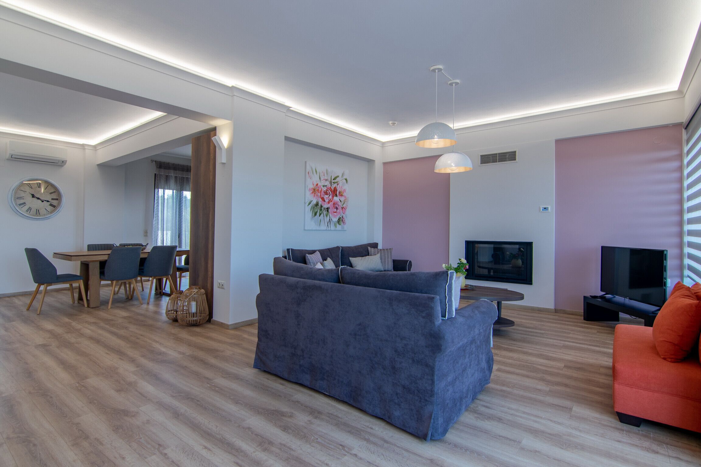 Uma sala de estar moderna com sofá, televisão e área de jantar.