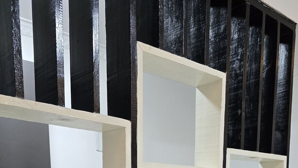 Um interior moderno com esquema de cores preto e branco, incluindo uma área de cozinha com micro-ondas e um cilindro de gás vermelho.