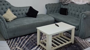 Uma sala de estar moderna com dois sofás cinzas, uma mesa de centro branca e um tapete estampado.
