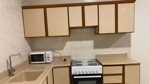 Cozinha compacta com micro-ondas, fogão e pia.