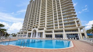 Um hotel alto com piscina e várias varandas.