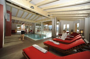 Uma área de spa com piscina, espreguiçadeiras vermelhas e vigas de madeira.