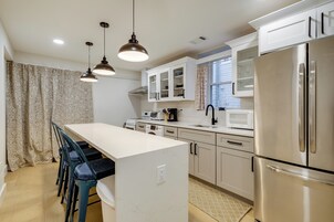 Uma cozinha moderna com armários brancos, eletrodomésticos de aço inoxidável e iluminação pendente.