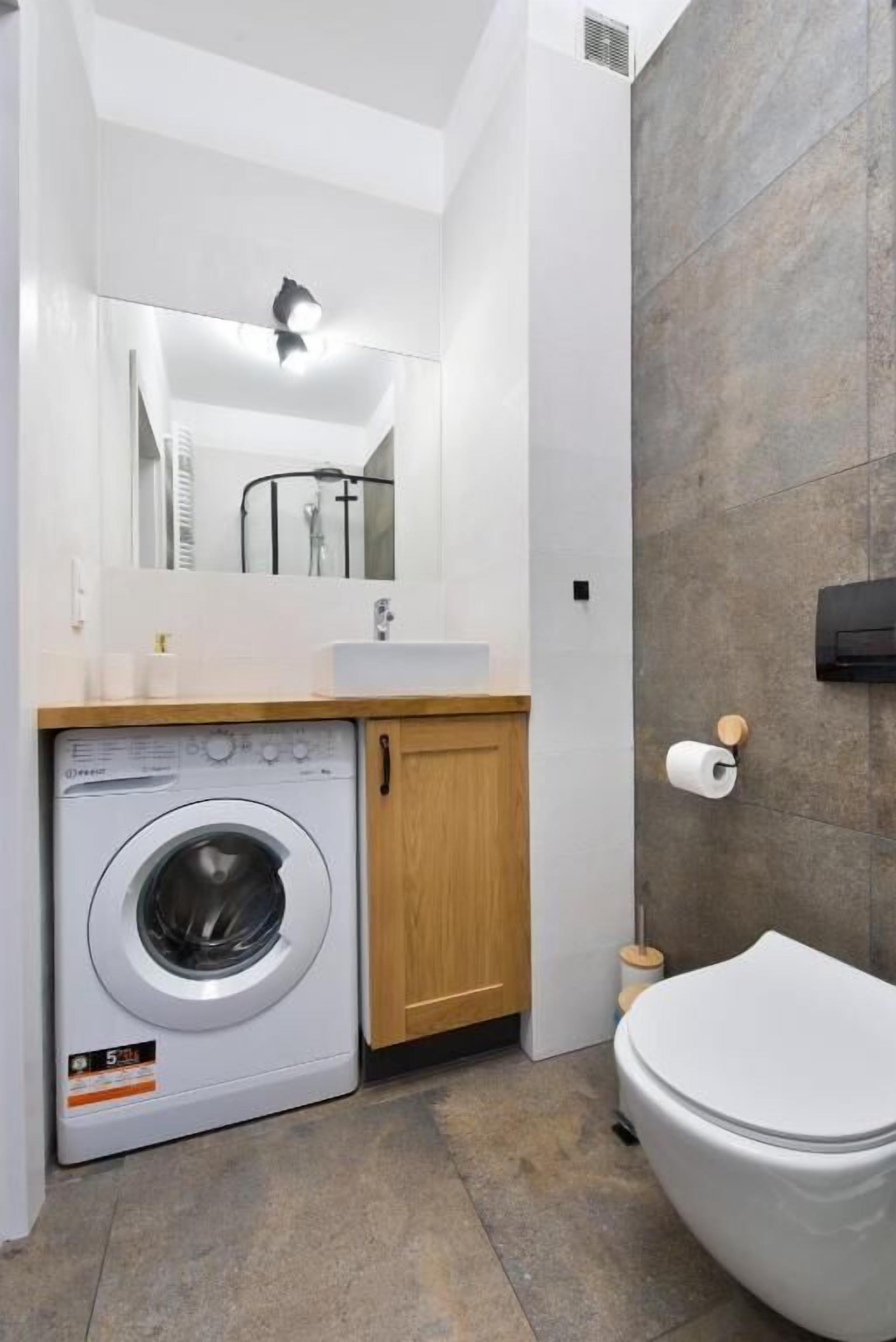 Casa de banho compacta com máquina de lavar roupa, sanita e lavatório.