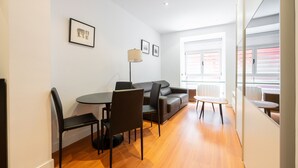 Uma sala de estar moderna com sofá, mesa de jantar, cadeiras e um abajur.