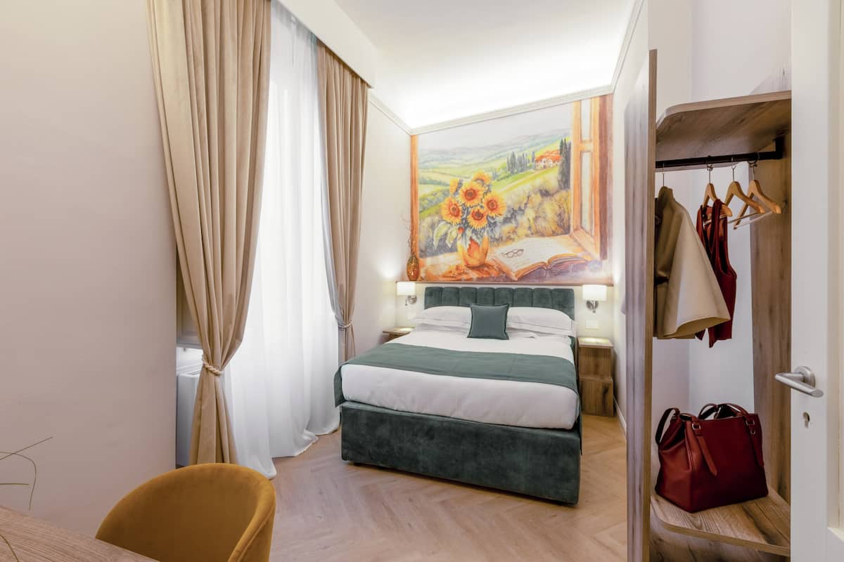 Quarto de hotel com cama, guarda-roupa, cadeira e um quadro na parede.