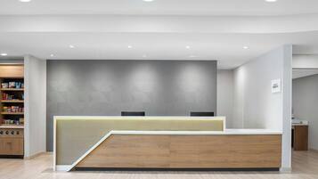 Uma receção com design moderno, balcão de madeira e parede decorada.