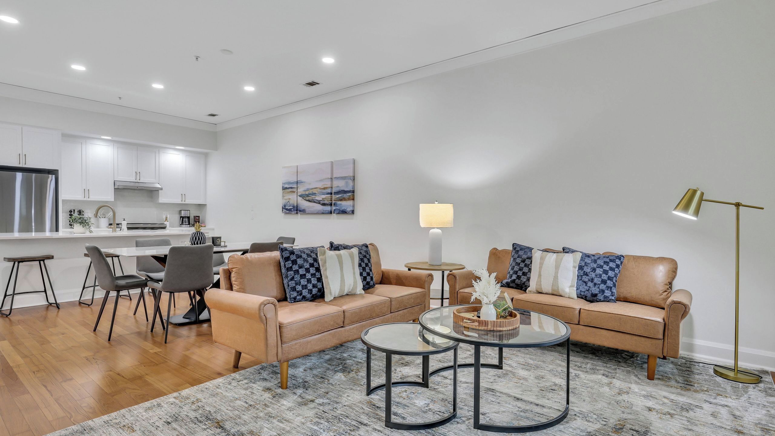 Uma sala de estar moderna com sofá, mesa de centro e área de jantar com cadeiras e mesa.