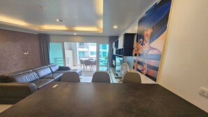 Sala de estar moderna com um sofá grande, uma mesa de jantar e vista para a área externa.