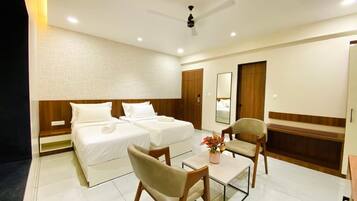 Quarto de hotel com uma cama, duas mesas de cabeceira, uma cadeira, uma mesinha e um espelho.