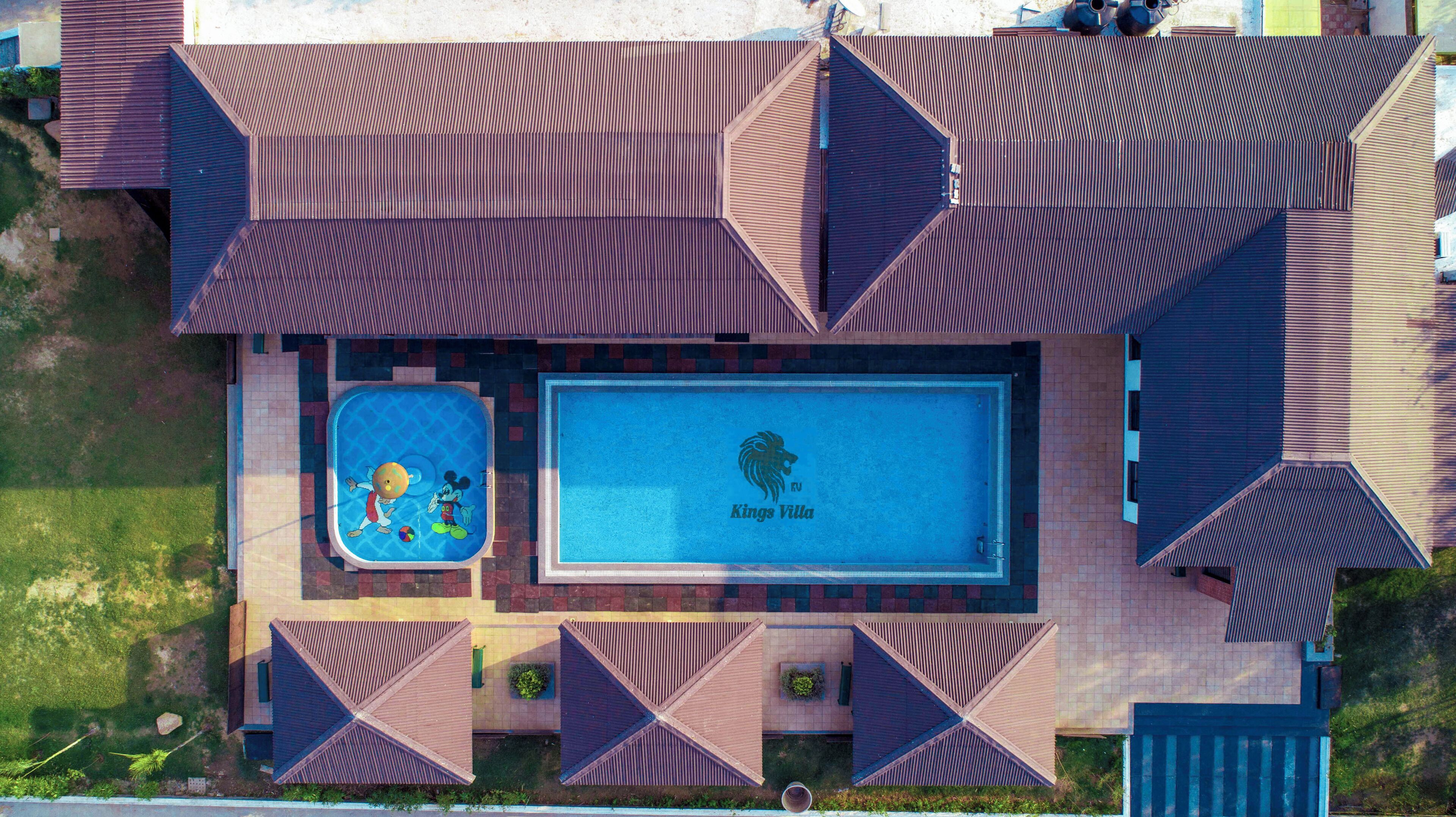 Vista aérea de um hotel com piscina, área de recreação infantil e jardim paisagístico.