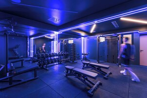 Uma academia com equipamentos de ginástica, esteiras e suportes para pesos.