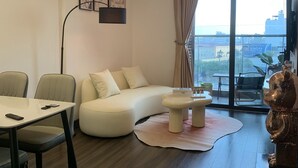 Uma sala de estar moderna com um sofá branco, uma mesa de jantar com cadeiras, uma mesa de centro e uma estátua dourada decorativa.