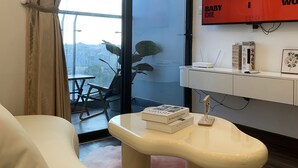 Uma sala de estar moderna com um sofá branco, uma mesa de centro branca e uma janela grande com cortinas.