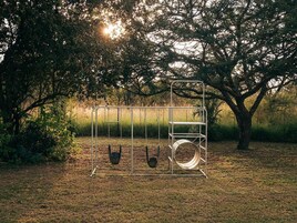 Um balanço de metal em uma área gramada, com árvores ao fundo.