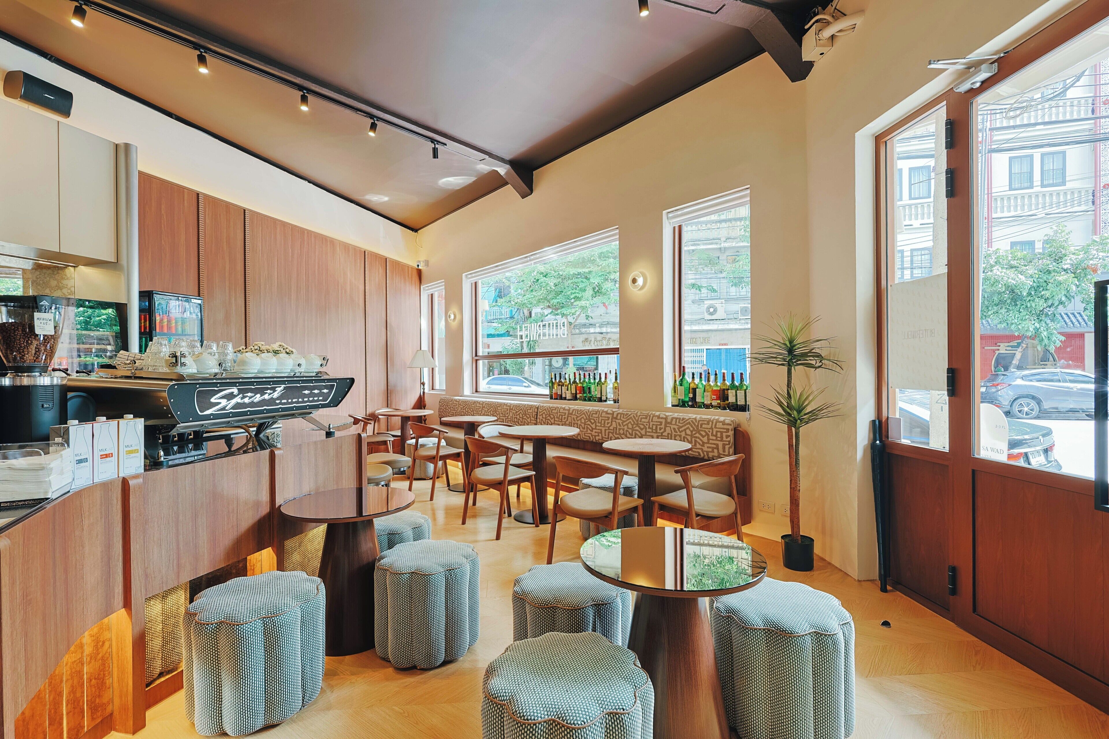 Interior de café com balcão, mesas e grandes janelas.