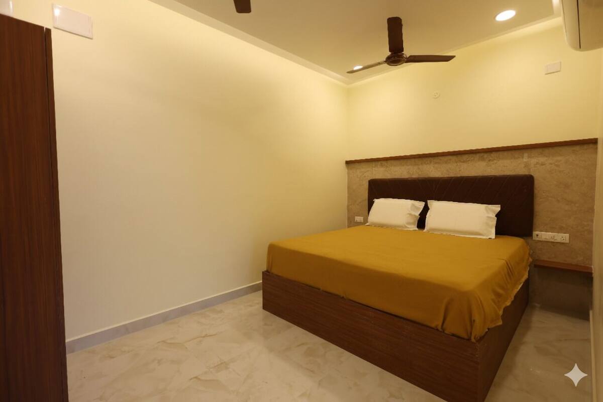 Quarto com cama, ventoinha no teto e interruptor de luz.