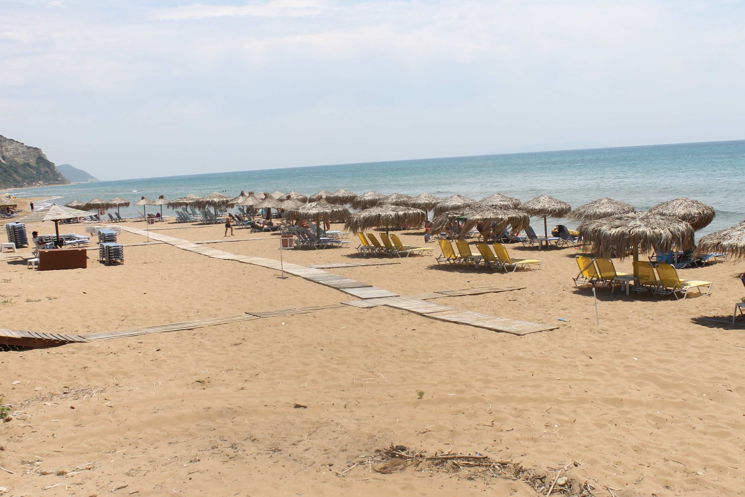 Uma praia com espreguiçadeiras e guarda-sóis de palha.