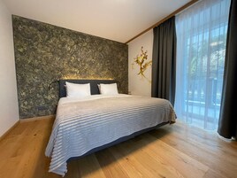 Quarto com cama grande, parede texturizada e janela com cortinas.