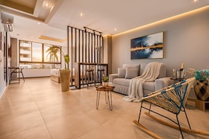 Uma sala de estar moderna com um sofá, uma mesa de centro, uma cadeira de balanço e uma janela grande com vista.