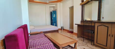 Um quarto com uma cama, uma mesinha, um banco, um espelho e um guarda-roupa.