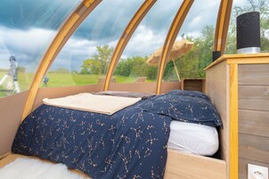 Um quarto aconchegante com uma cama, um penteou de madeira e vista para o exterior.