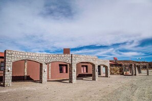 Um edifício rústico com arcos de pedra e paredes vermelhas, apresentando vários quartos com janelas e portas.