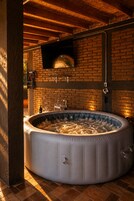 Uma banheira de hidromassagem em um quarto com paredes de tijolo e vigas de madeira.
