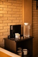Um espaço com café, máquina de café, dispensador de água e suporte para canecas.