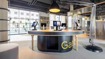 Um balcão de recepção moderno com design circular, uma estação de check-in digital e uma placa visível com a palavra 'Gate'.
