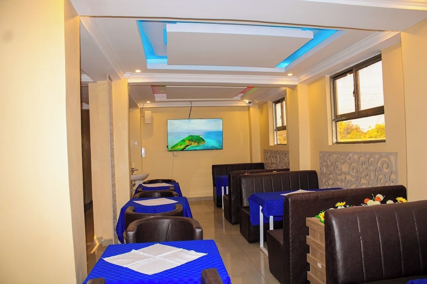 Um restaurante com cabines e mesas, uma tela de televisão e uma janela com vista.